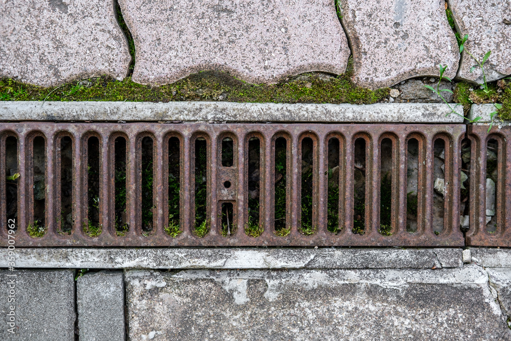 Rusty metal grating of a gutter for draining rainwater among concrete ...