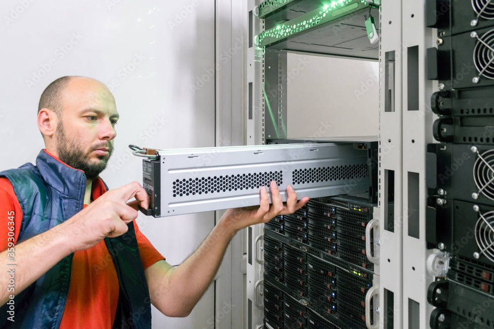 The specialist installs a new battery in the uninterruptible power ...