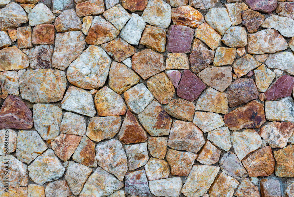 colored unprocessed rocky stones of natural origin, a wall of stones in ...