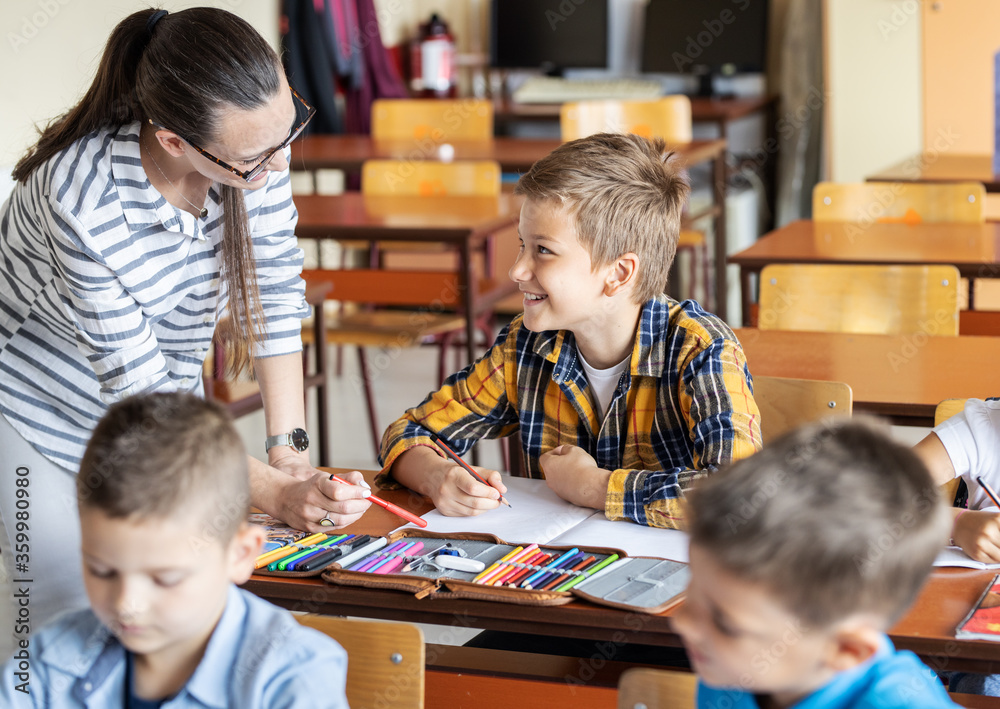 Female teacher helping school boy to learn lesson. Primary school ...