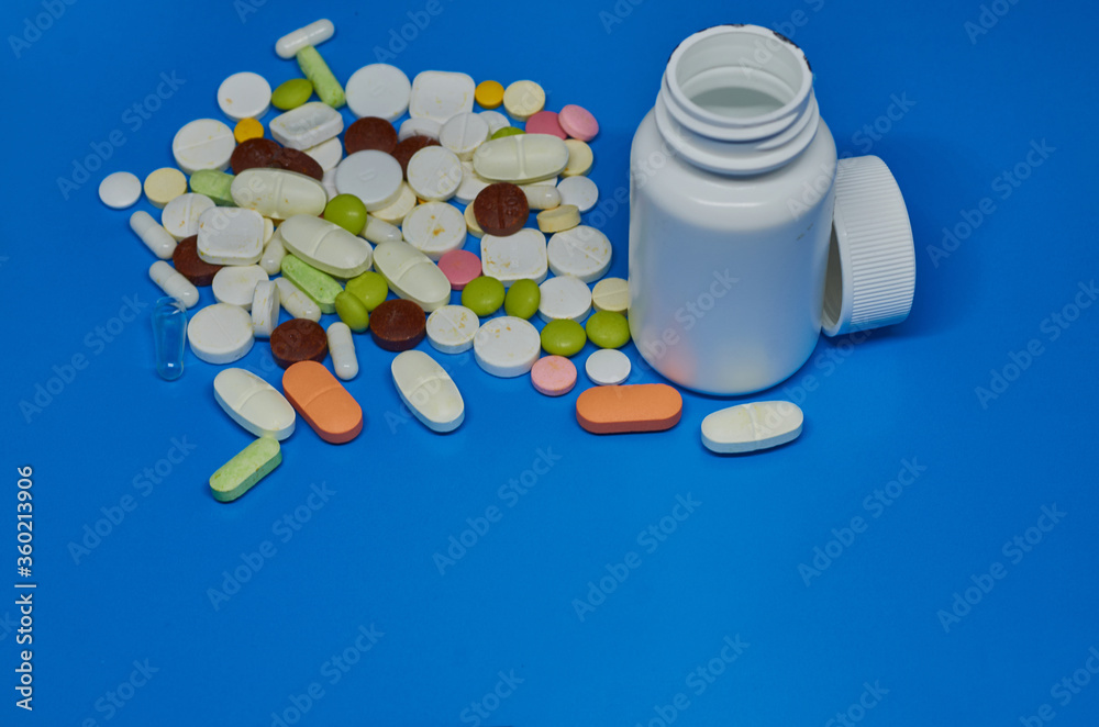 Pills of different colors and ampoules with medicine on a blue ...