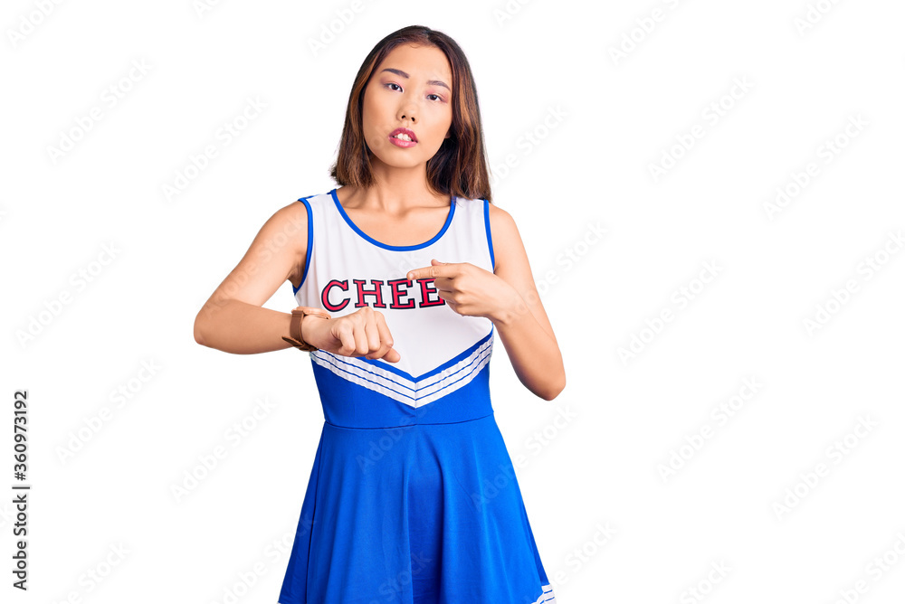 Young beautiful chinese girl wearing cheerleader uniform in hurry ...