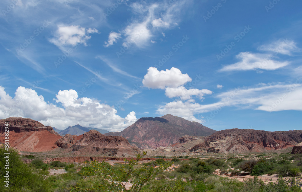 Paisaje arido de montañas y nubes en un dia soleado con cielo azul ...