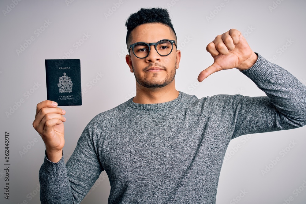 Young handsome tourist man on vacation wearing glasses holding Canada ...