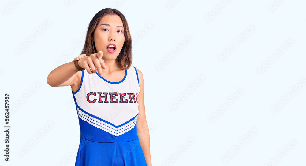 Young beautiful chinese girl wearing cheerleader uniform pointing ...