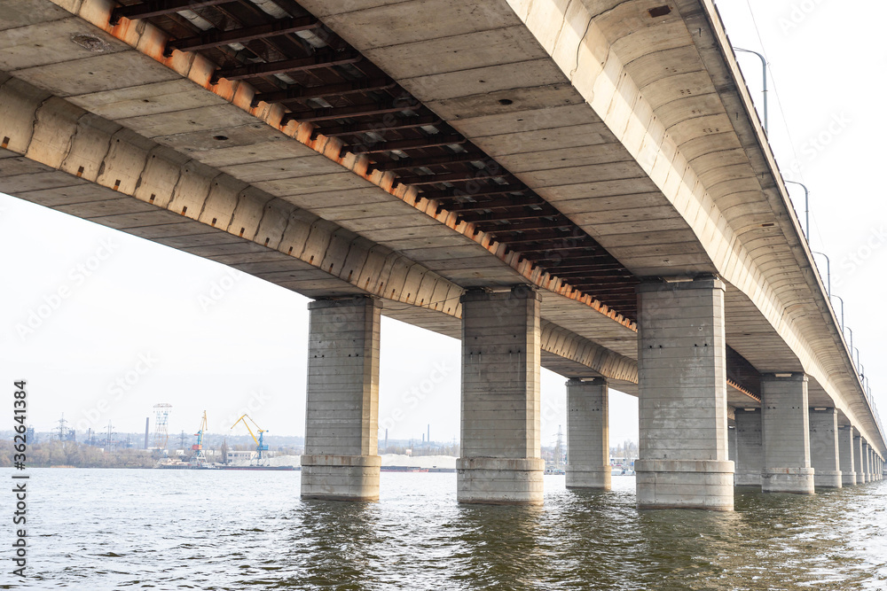 Row of grey concrete pillars of the bridge over the river. Bridge piers ...