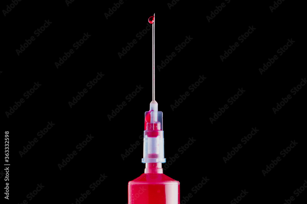 Horizontal image of syringe with a drop of blood at the tip of it's ...