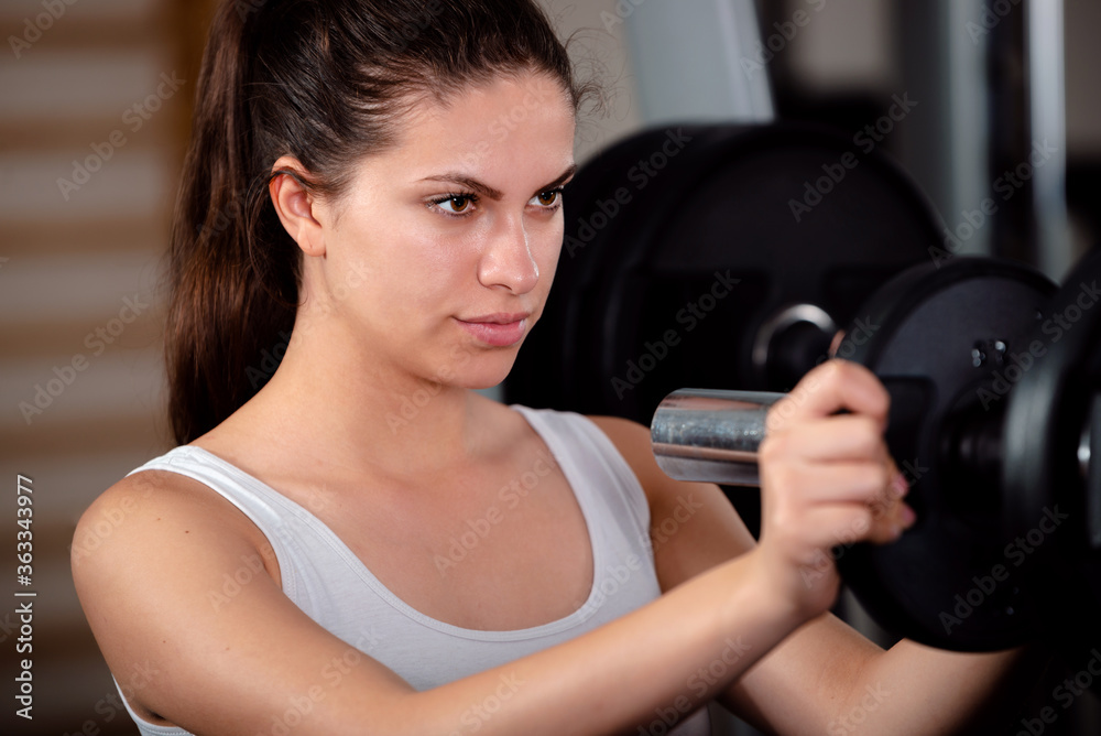 Very beatiful teenage girl workout in gym. Young female athlete put ...