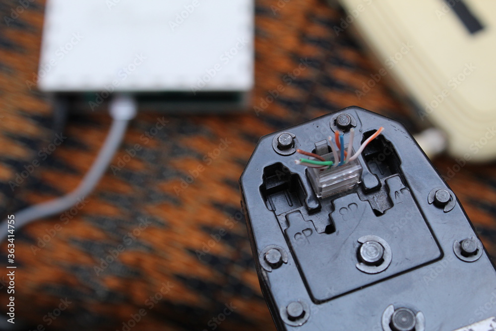 Selective focus to RJ45 Connector with crimping RJ45 tool on blurry ...