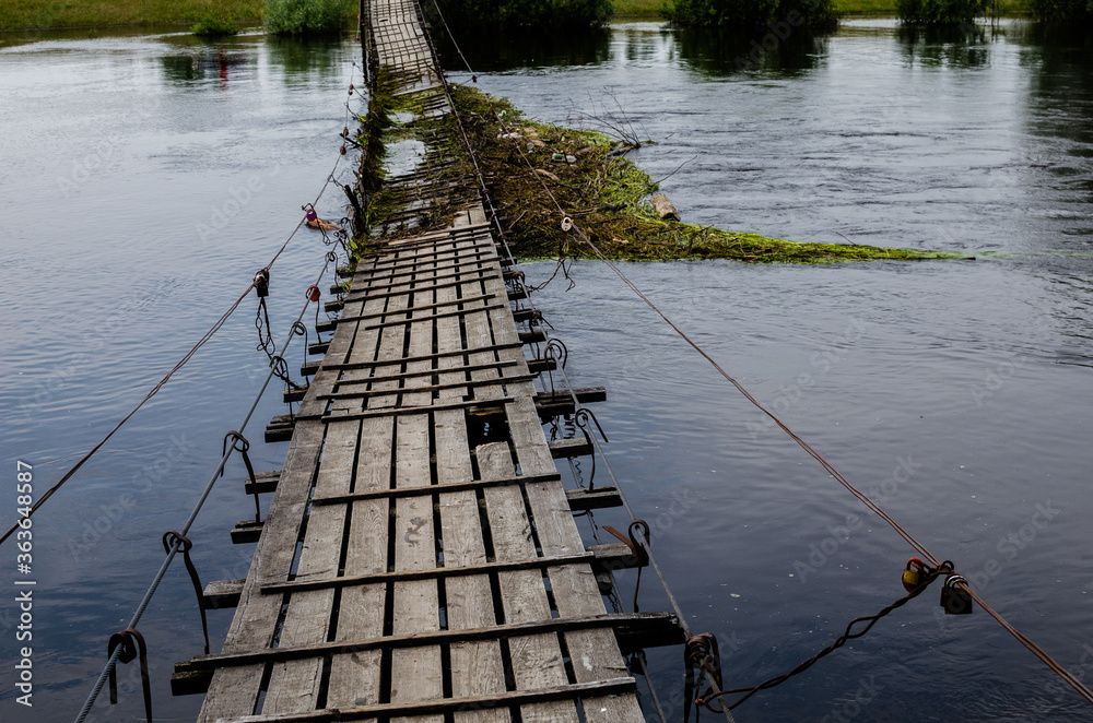 Suspension bridge over the river is broken and flooded. The ...