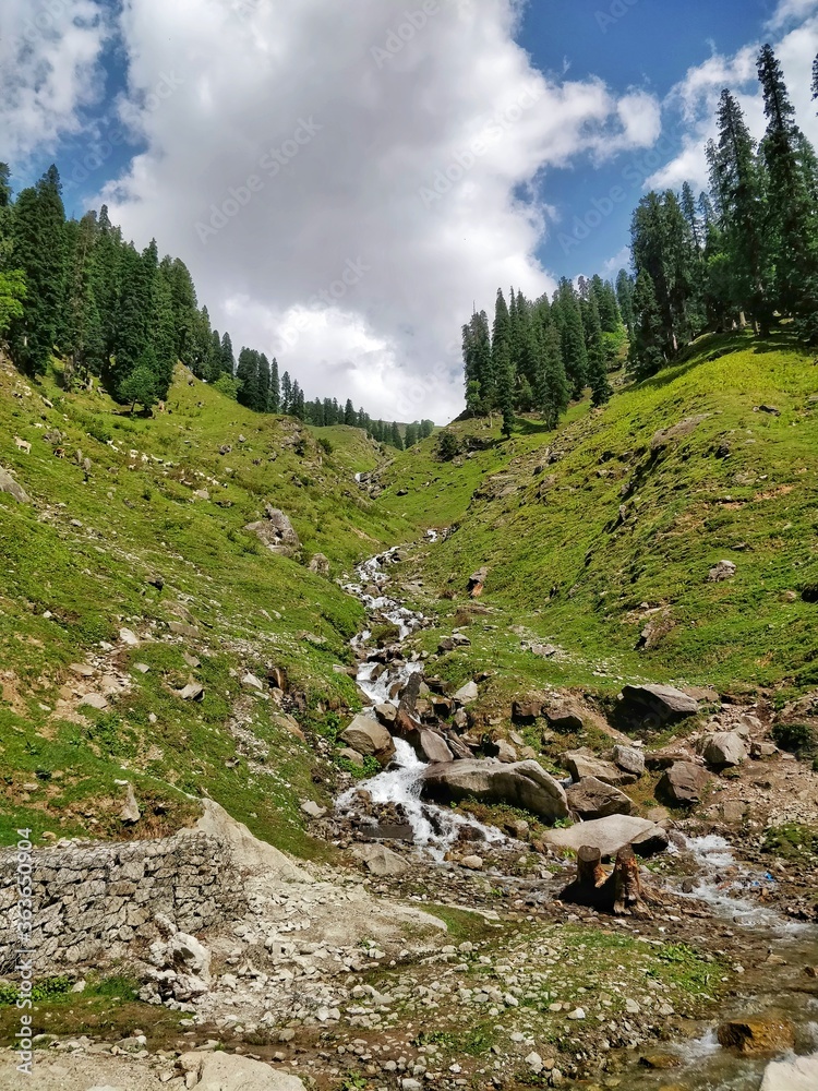 Beautiful stream of water flowing through rocks, stones of steep slope ...