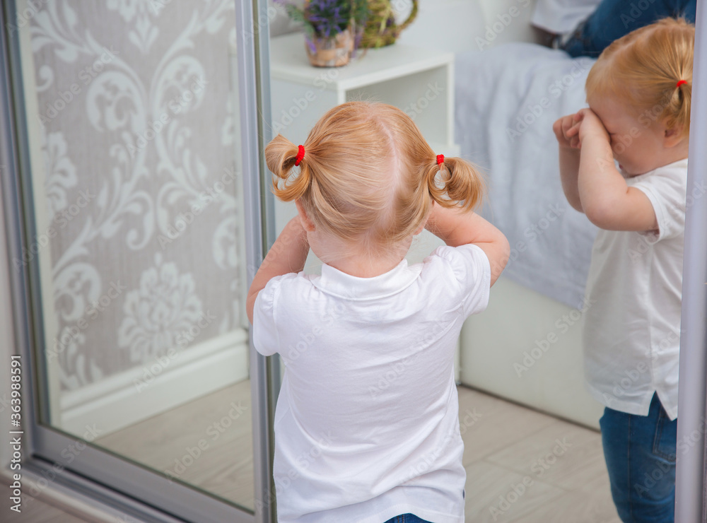 Foto Red-haired little girl crying at the mirror. Cute little girl ...