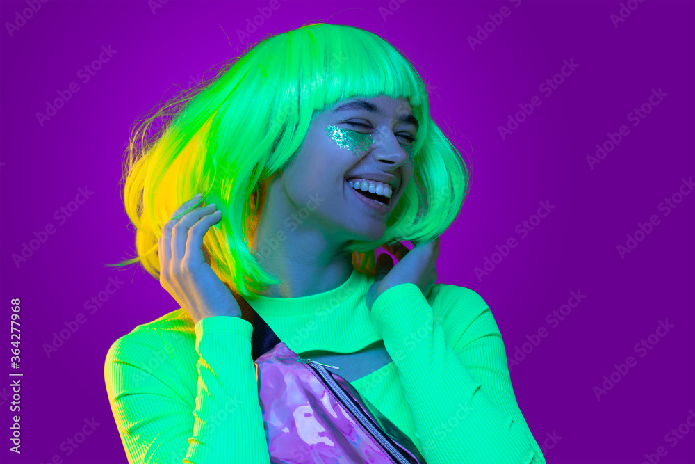 Teen laughing girl wearing neon green top, moving her head in dance so ...