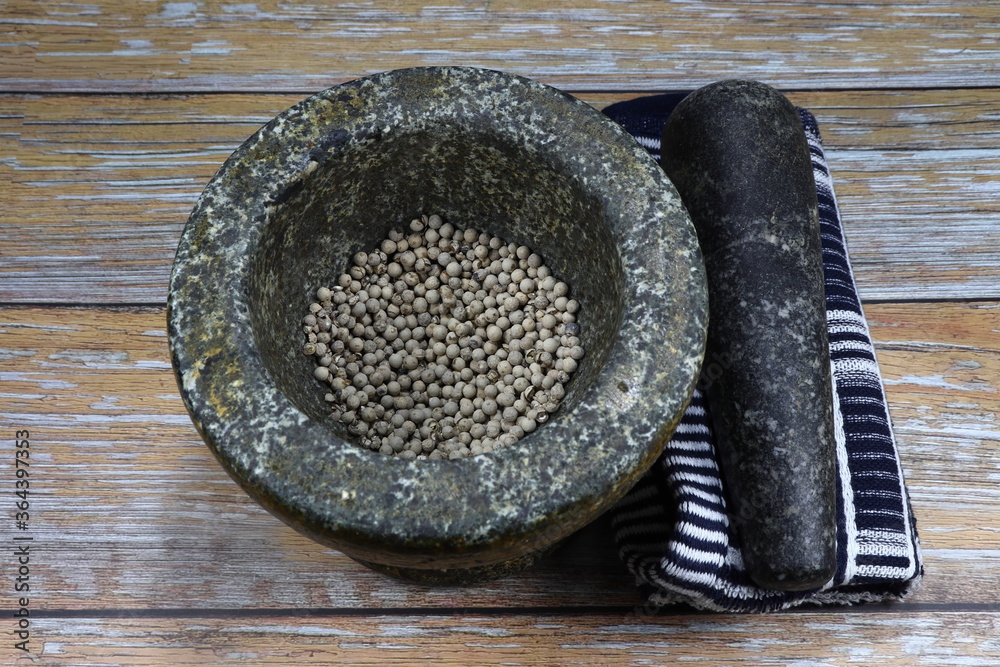 Fresh white pepper seed inside the stone mortar (marble mortar) ready ...
