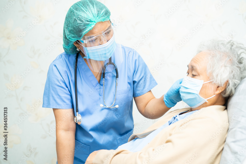 Asian doctor wearing face shield and PPE suit to check patient protect ...