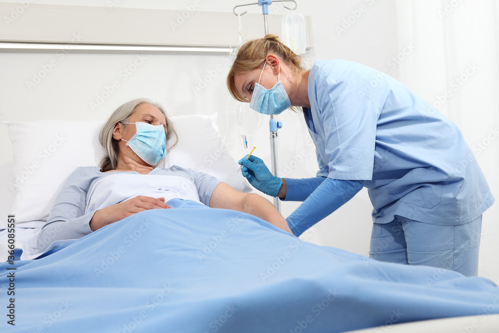 nurse with the syringe injects the vaccine to the elderly woman patient ...