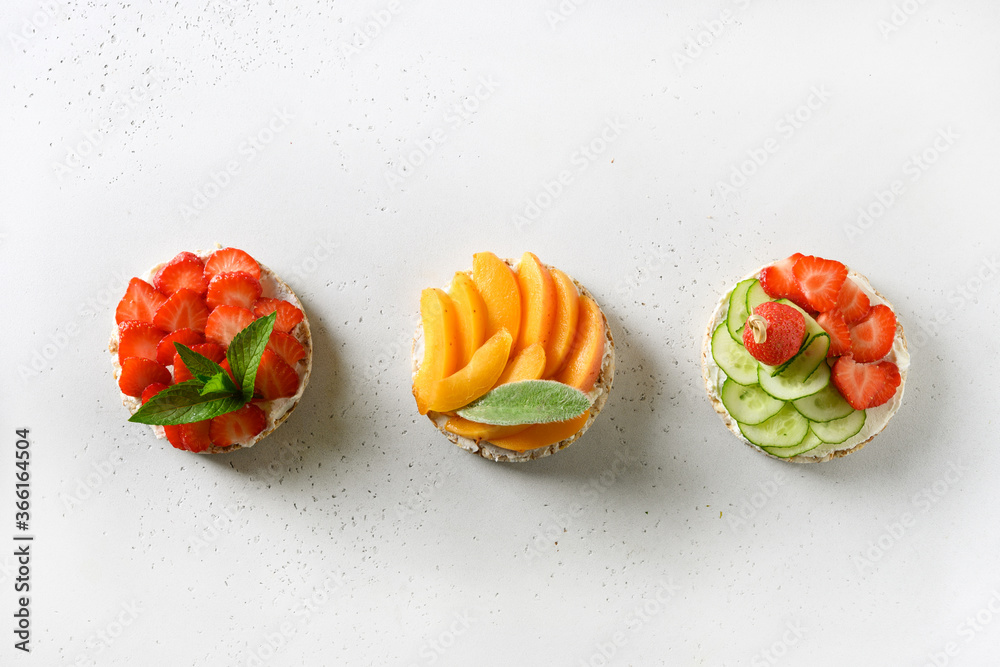 Rice crispbread with different toppings friuts and vegetables on white ...