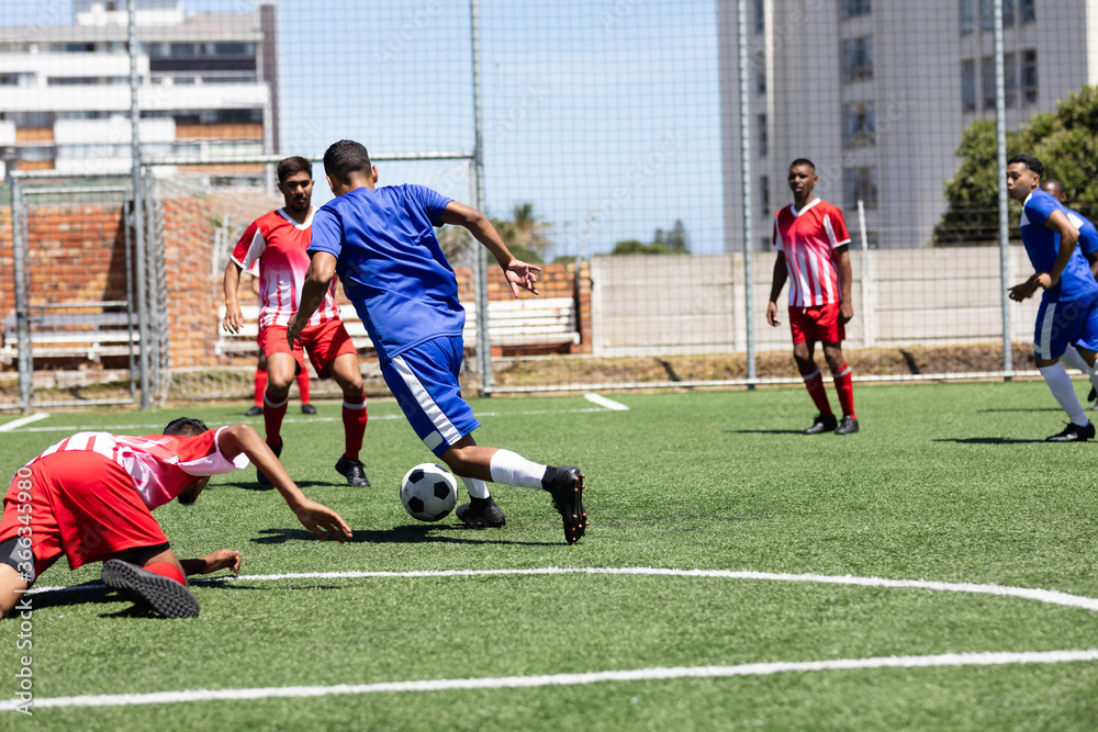 Multi ethnic team of male football players training at a sports field ...