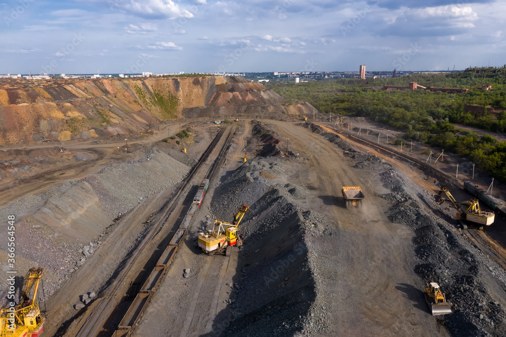 Excavator and heavy mining dump trucks in a limestone quarry, loading ...