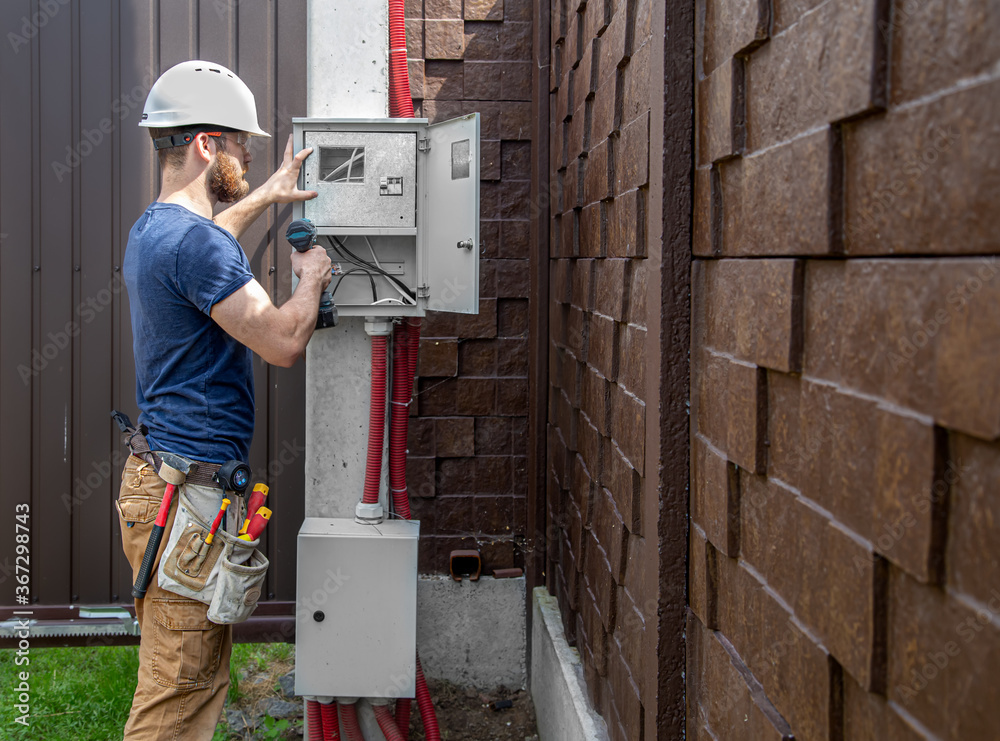 Electrician Builder at work, examines the cable connection in the ...