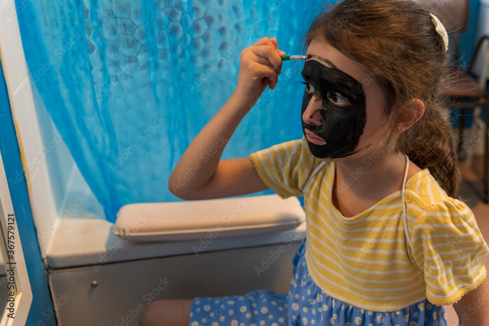A young girl from poor deprived family is entertaining herself by face ...
