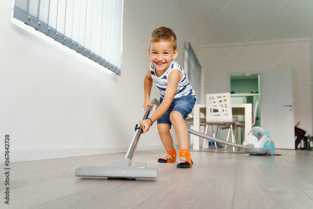 Little kid using vacuum cleaner at home - Small boy cleaning floor in ...