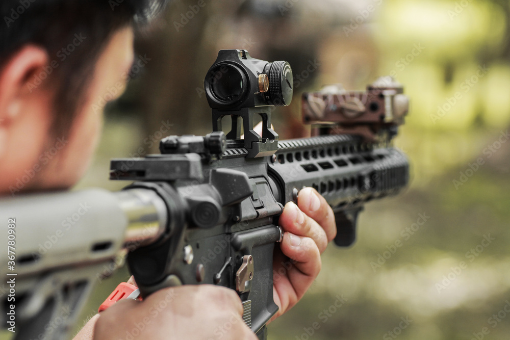 Military shooter with his precising assault rifle aiming and shooting ...
