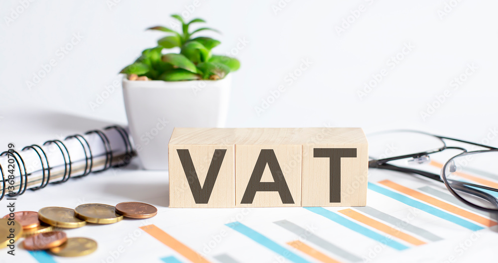 VAT word on wood blocks concept with chart, coins, notebook and glasses ...
