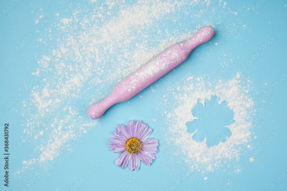 Lavender colored rolling pin with sprinkled flour. Baby blue background ...