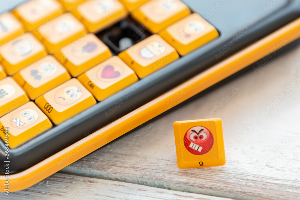Button with an angry emoticon on the keyboard background. Close up ...