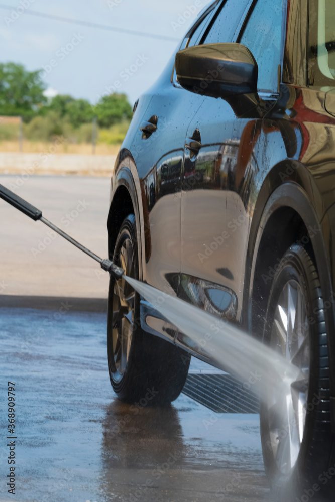Front wheel of a car being rinsed using a high pressure water spray ...