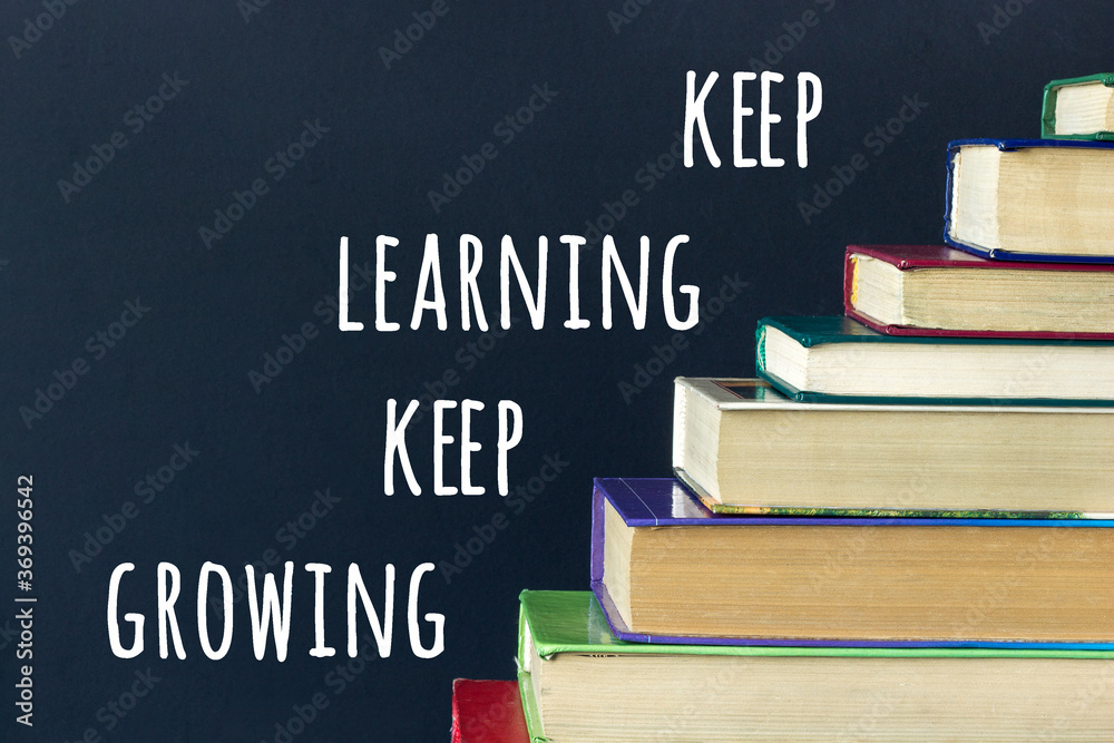 Keep learning Keep growing text and stack steps stairs of old books on background black ...