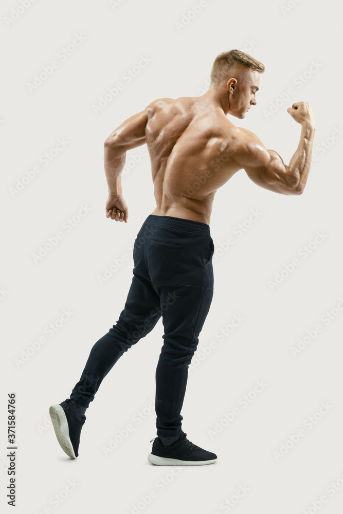Strong back of a athletic muscular man flexing his arms against grey ...