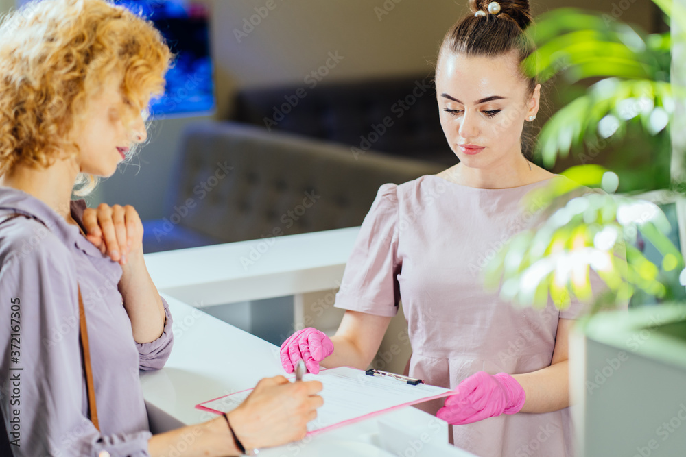 Female receptionist working with visitor in medical office. Visitor ...