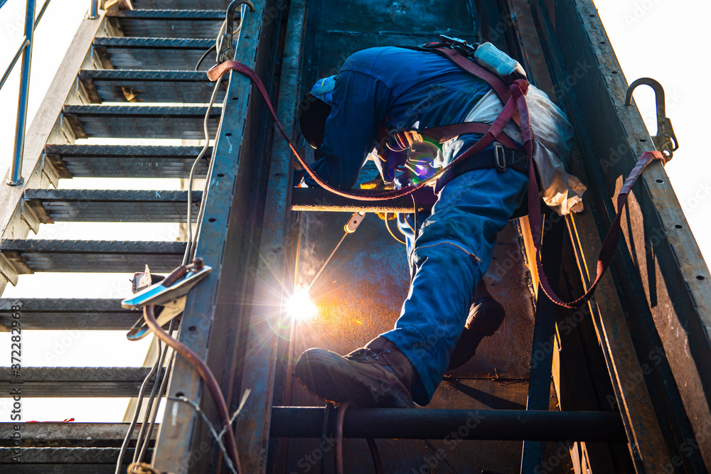 Welder is welding the steel plate by process shielded metal arc welding ...