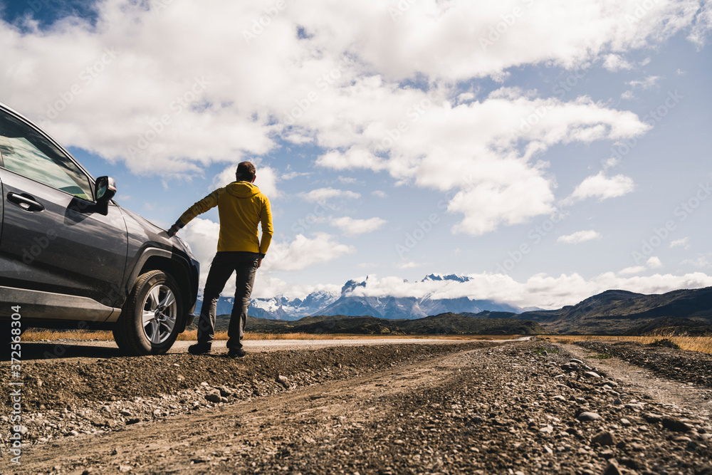 Mature man standing by car on dirt road at Torres Del Paine National ...