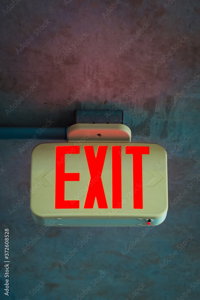 Illuminating rectangular bright red exit sign attached to shabby ...