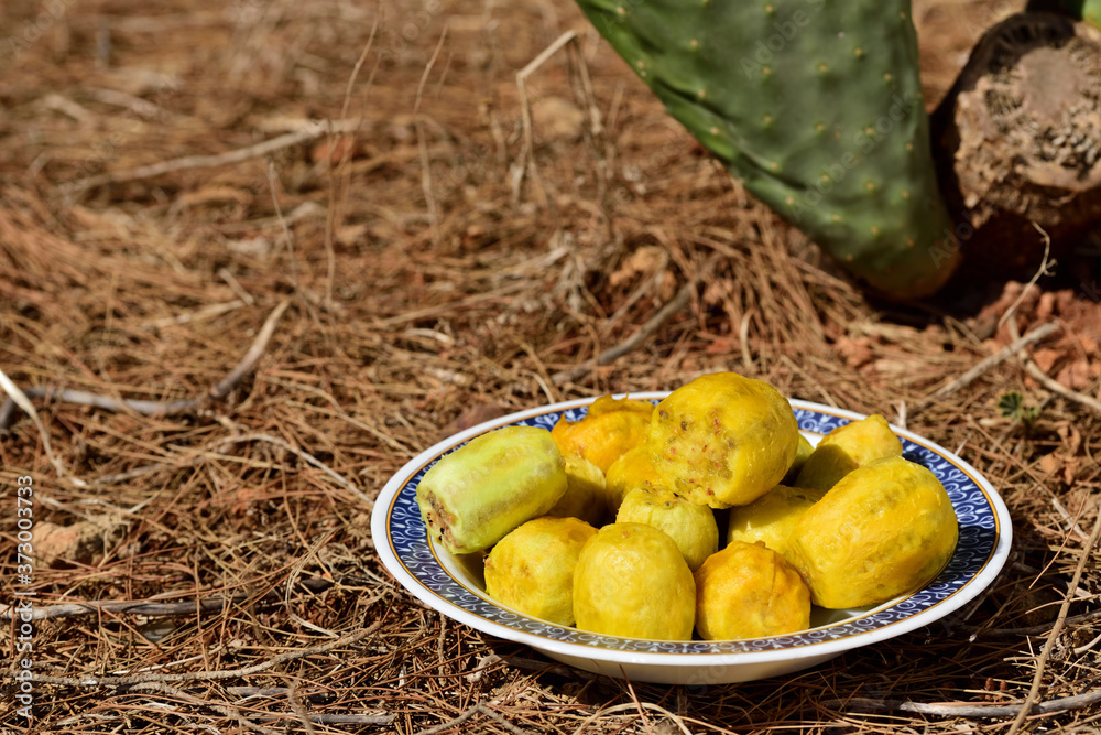Fresh peeled prickly pears lie in an old plate, in front of a prickly ...