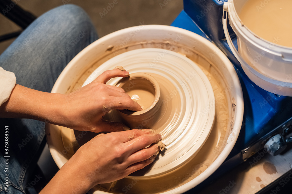 beautiful hands of a young girl, stained with clay when modeling a pot ...