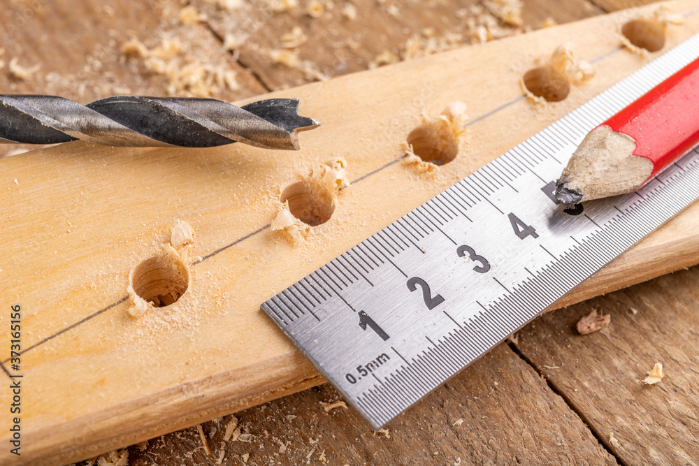 Creating holes with a metal drill in a piece of wood. Metal ruler for ...