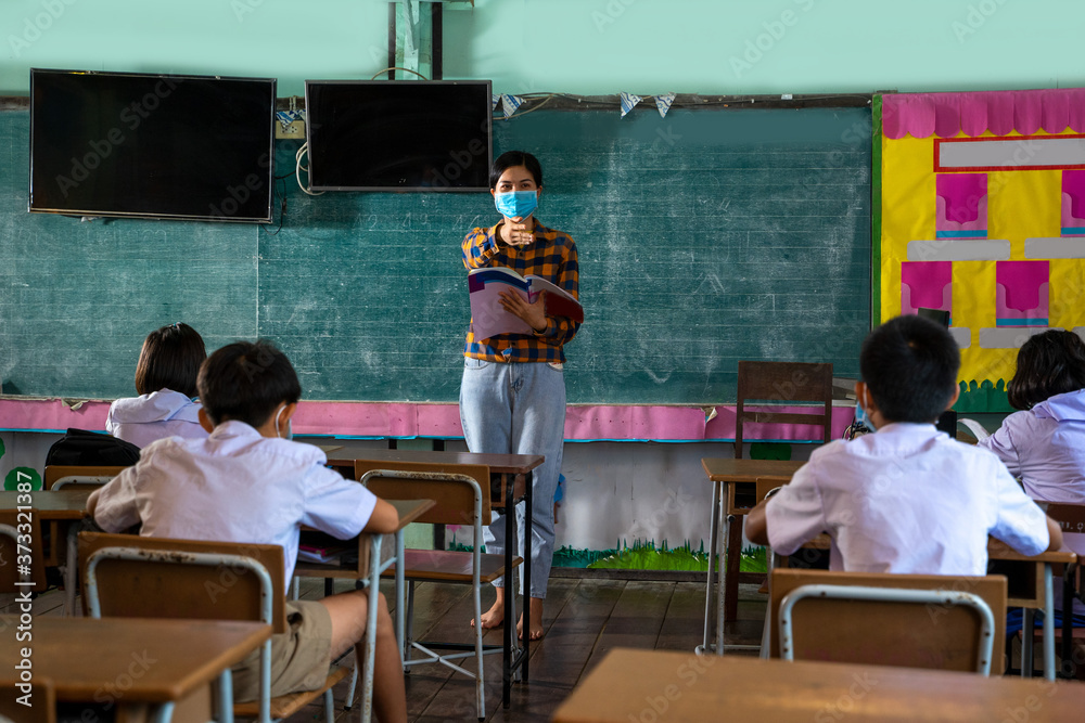 Students and her teacher wearing protective face masks in classroom at ...