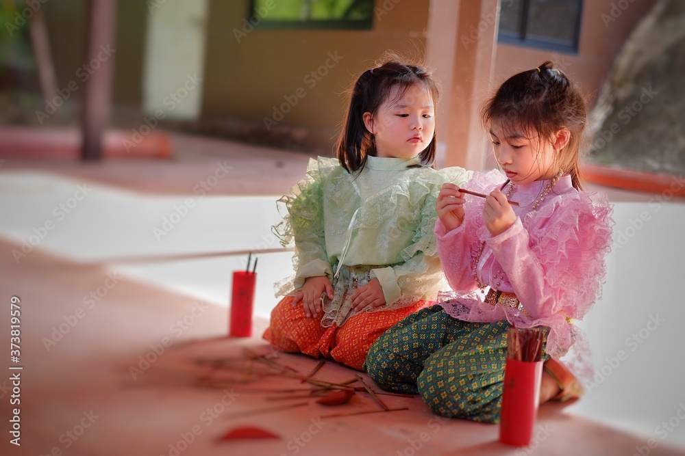Cute young Asian girls in traditional Thai costumes are shaking chi-chi ...