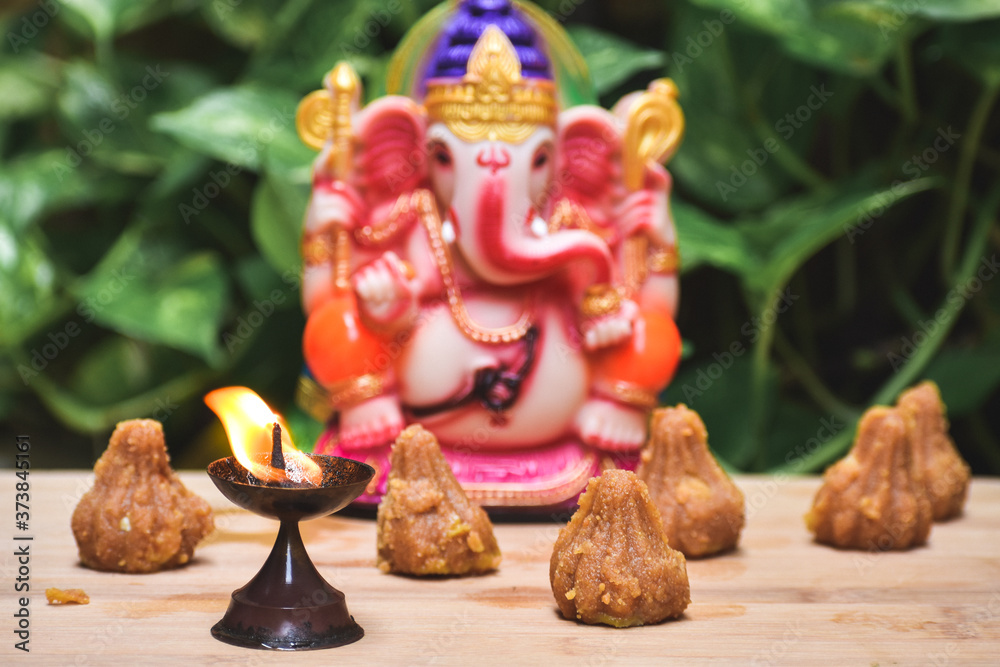 Close up shot of Diya in front of statue of lord Ganesha during the ...