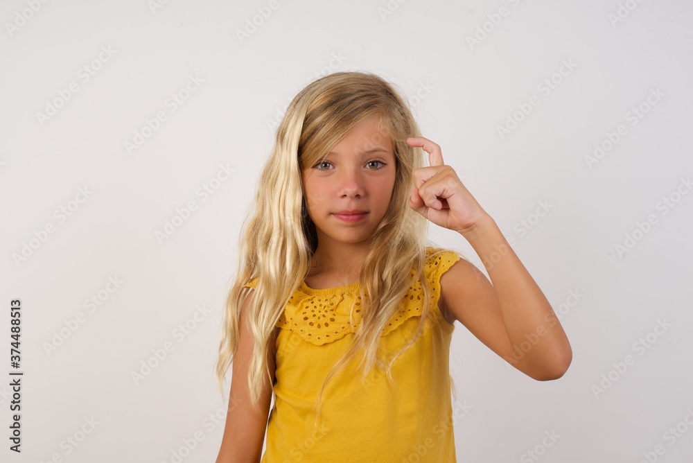 Little girl with beautiful blonde hair over white background pointing ...