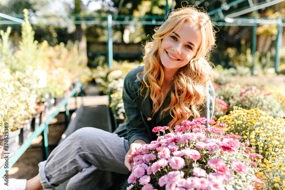 Against background of bright flowering plants and green bushes that ...