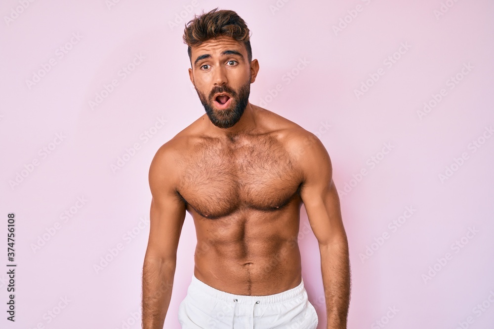 Young hispanic man standing shirtless afraid and shocked with surprise ...