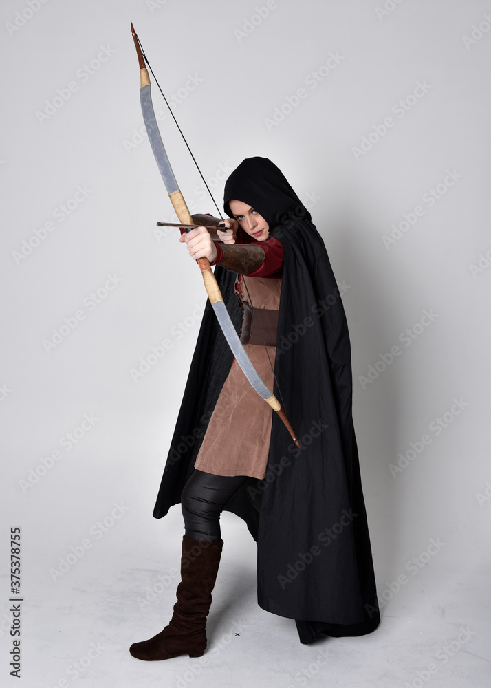 Full length portrait of girl with red hair wearing medieval archer ...