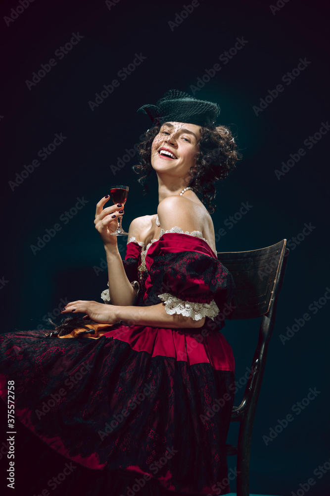 Wine and smile. Young woman as Anna Karenina isolated on dark blue ...