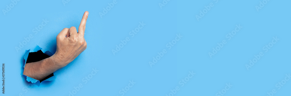 Hand shows the gesture of the middle finger on a blue background ...