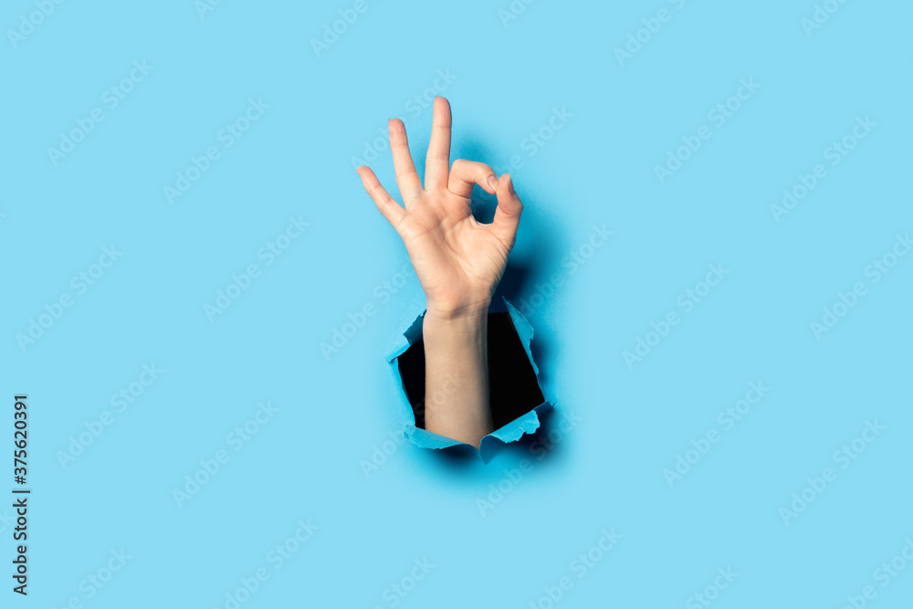 Hand makes a gesture everything is OK on a blue background. Gesture all ...